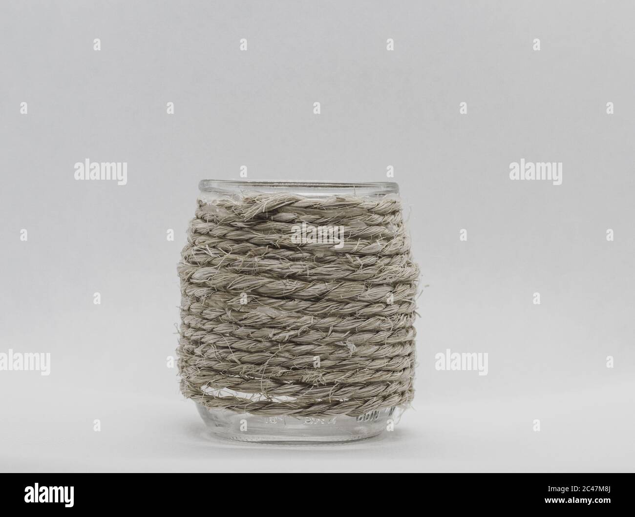 Glass container wrapped in a thick rope isolated on a white background ...