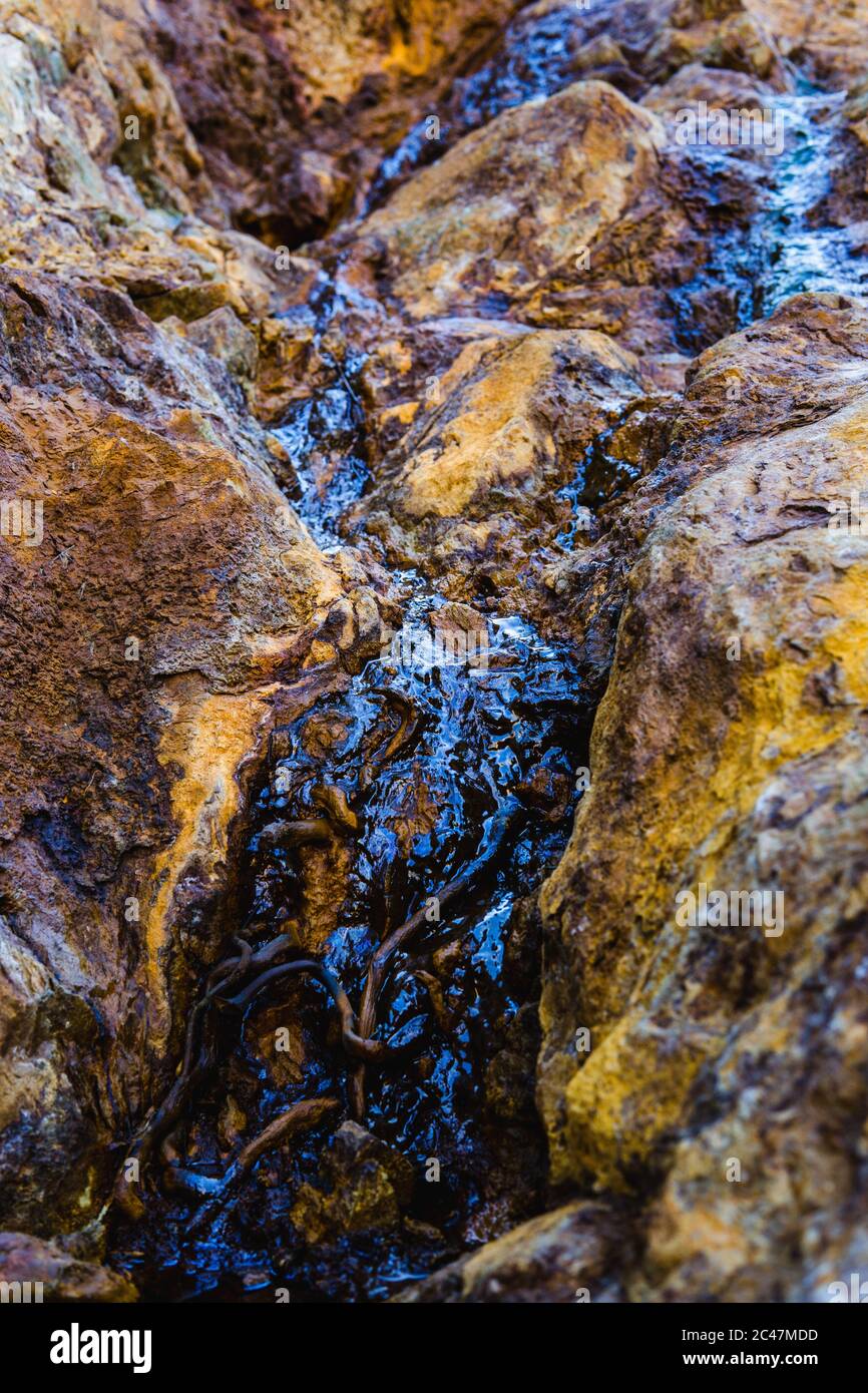 Closeup vertical shot of water running through the rocks at Rio Tinto ...