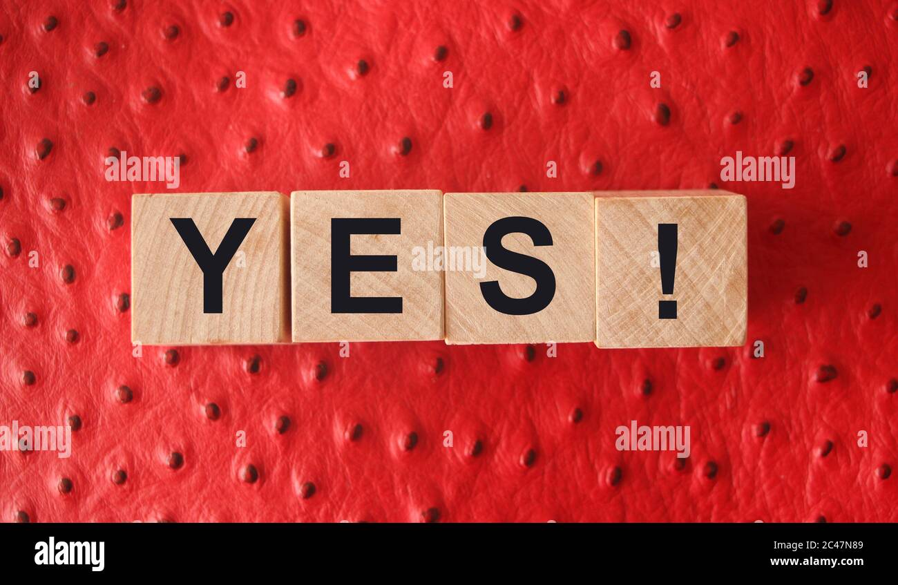The word Yes written in black letters on wooden blocks. on red leather ...