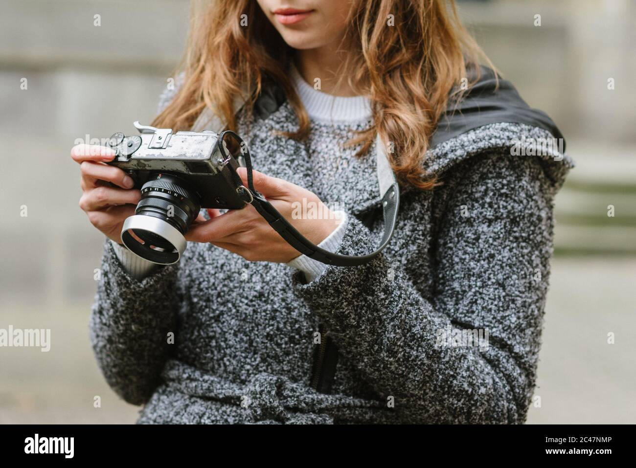 Attractive woman wearing a gray coat holding a vintage camera and ...