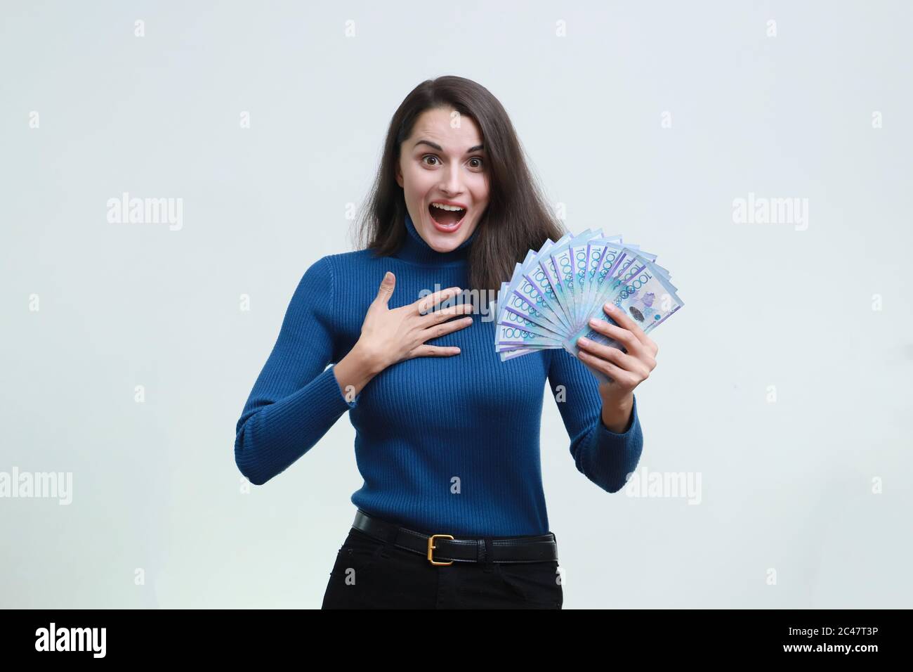 A beautiful woman has fun winning tenge money. Uniform white background ...