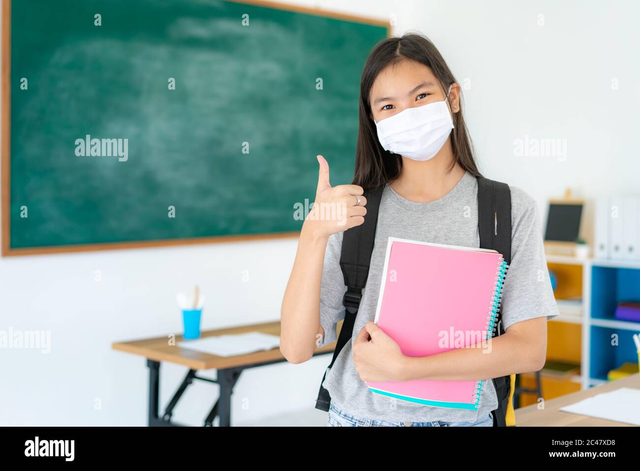 Asian primary student girl thumb up and wearing masks to prevent the ...