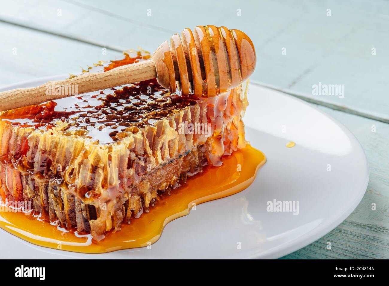 Honeycomb on plate with honey dipper Stock Photo - Alamy