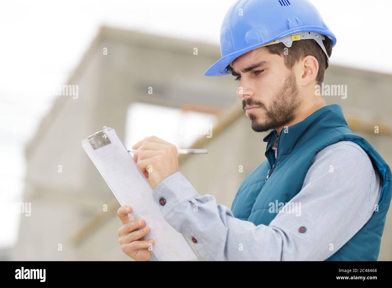 portrait of serious builder man writting on clipboard Stock Photo - Alamy