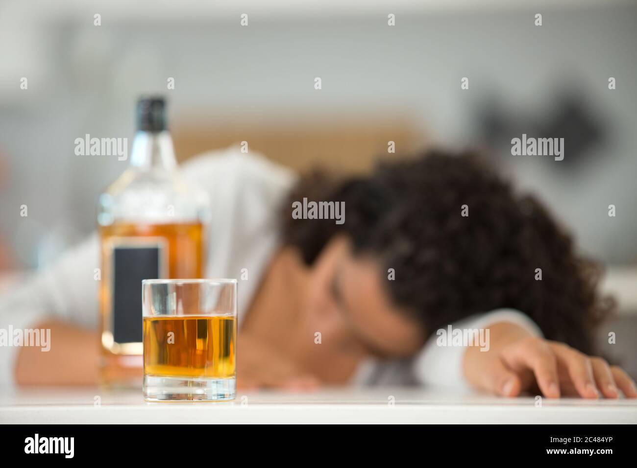 woman slumped over beside a bottle of alcohol Stock Photo - Alamy