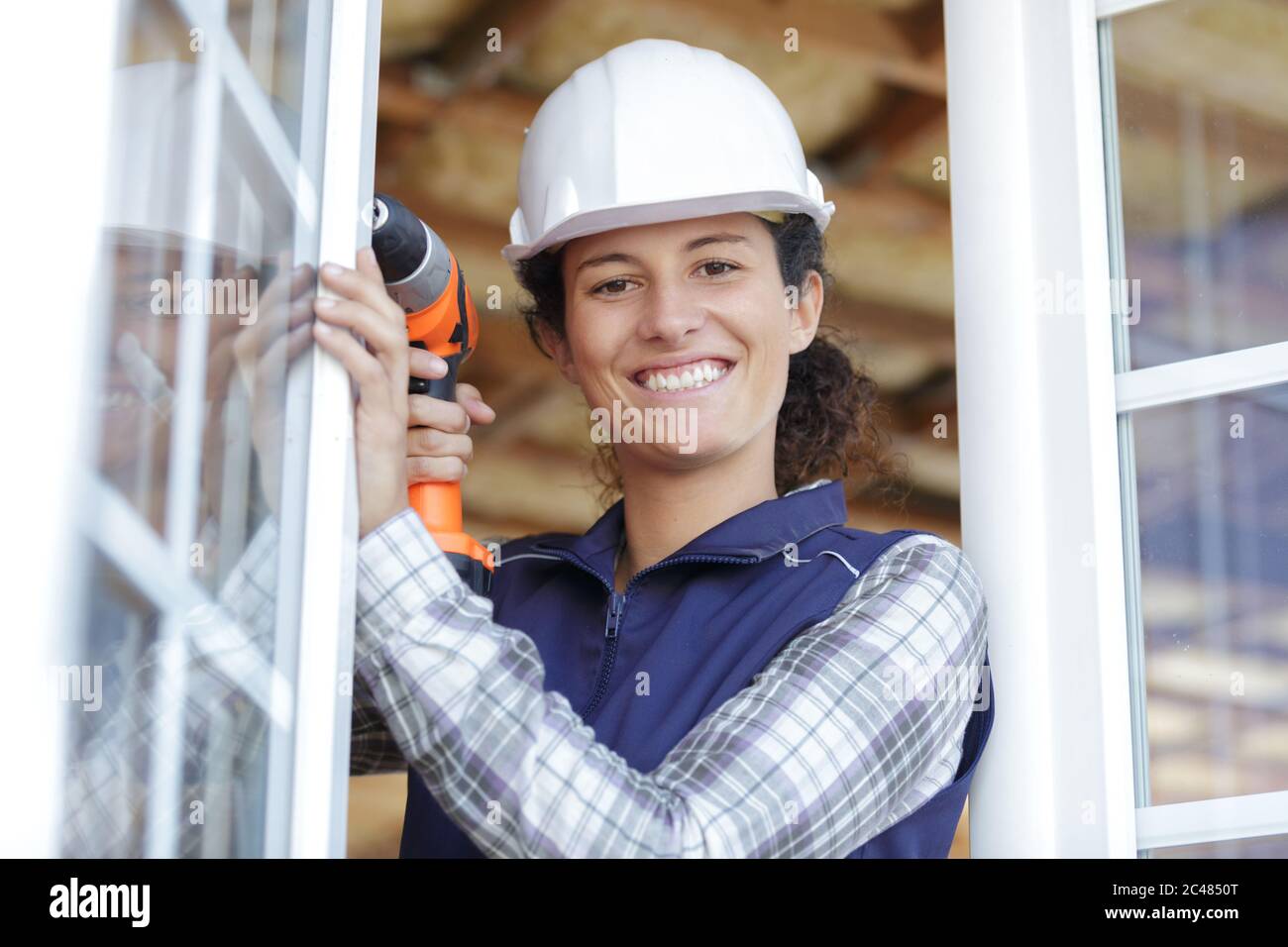 woman builder using a drill for fixing a window Stock Photo - Alamy