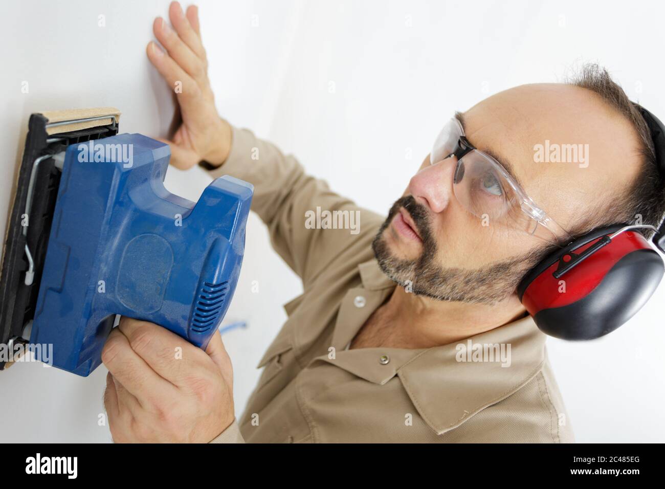 man sanding a wall with a power sander Stock Photo - Alamy
