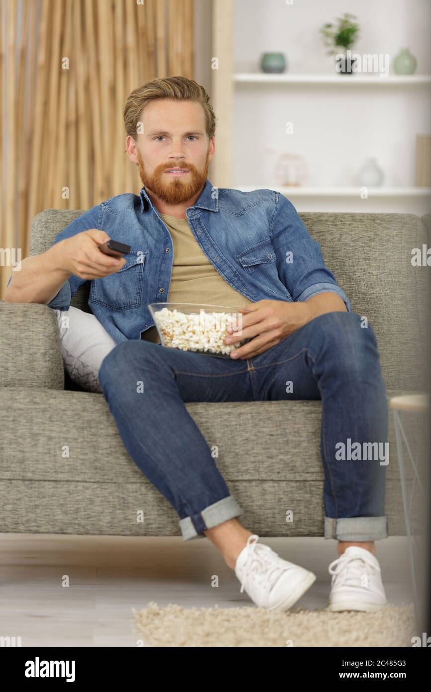 portrait an attractive man eating pop corn while watching tv Stock ...