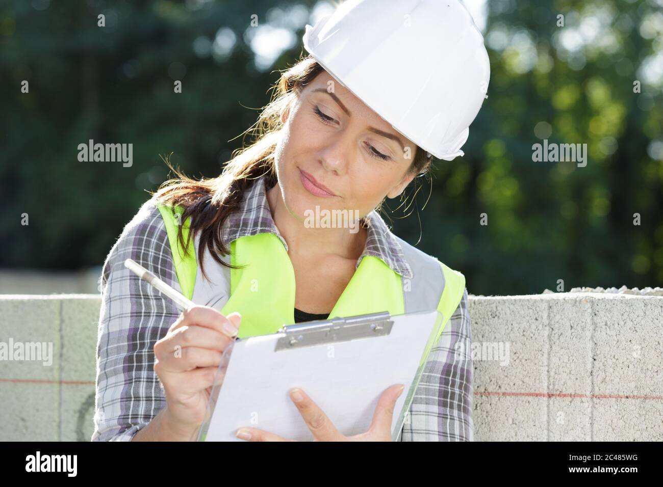 woman builder writing something in clipboard at construction site Stock ...