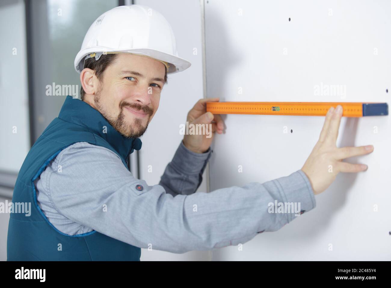 male builder measuring a wall Stock Photo - Alamy