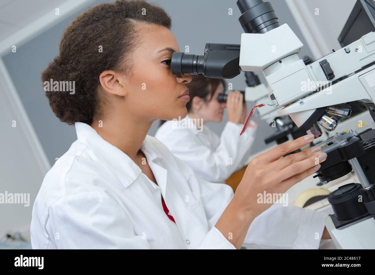 female scientist looking through a microscope in laboratory Stock Photo ...