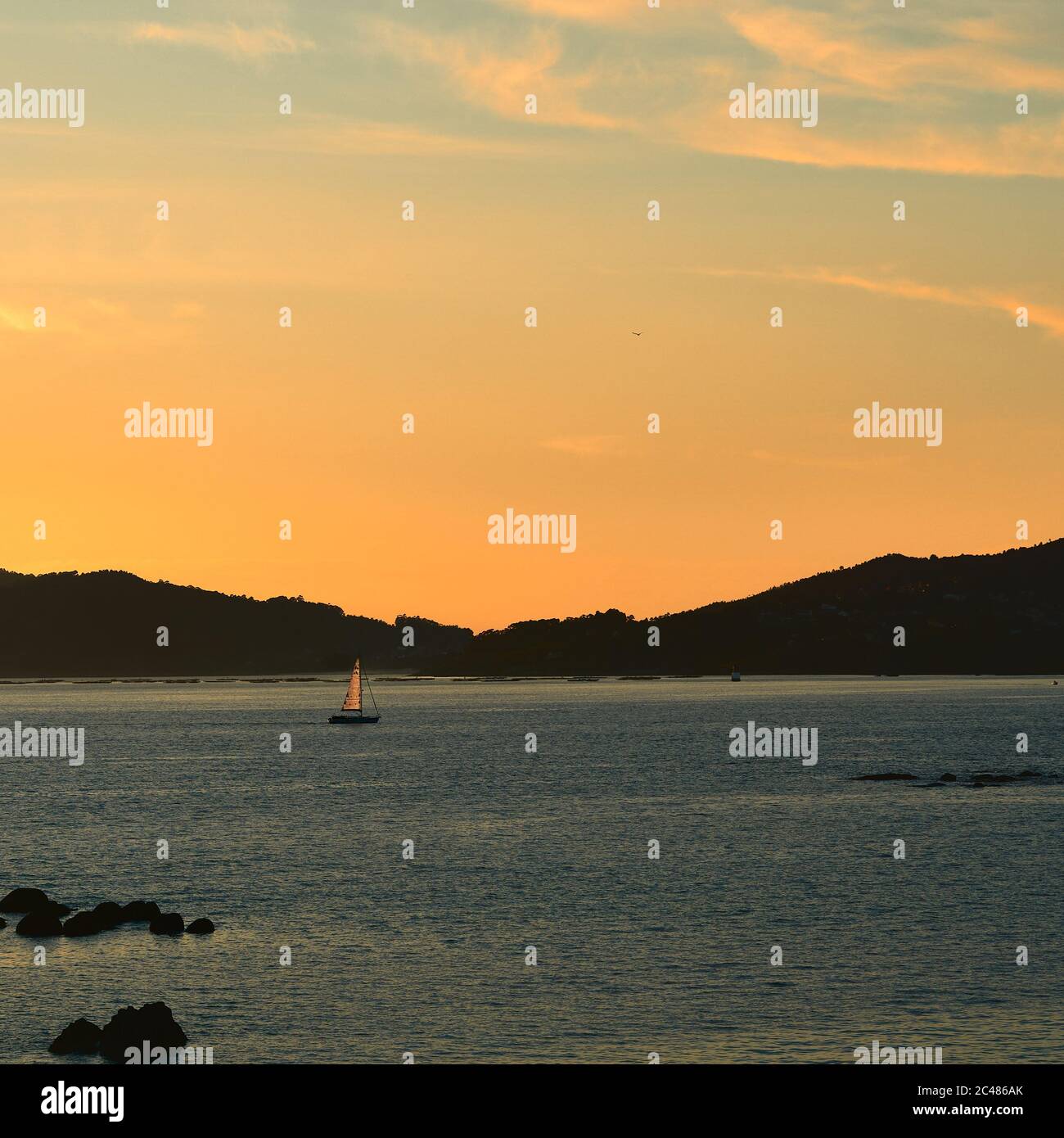 Breathtaking shot of the sea and the hills gleaming under the golden ...