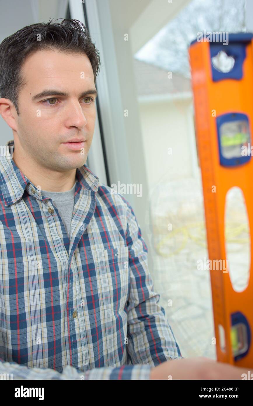 man checking upright surface with spirit level Stock Photo - Alamy