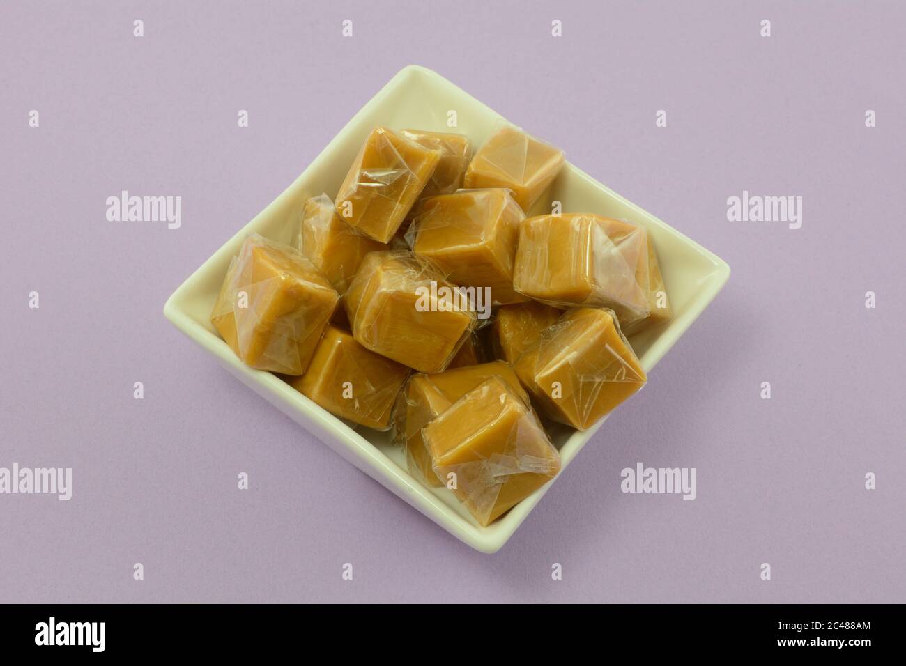 Caramel candy squares in individual plastic wrappers in white candy ...
