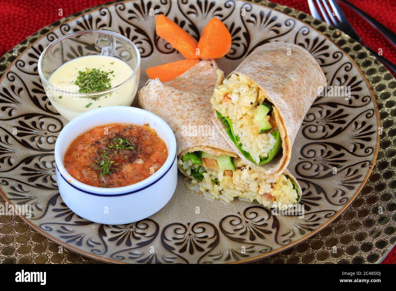 Burrito cut in half and some sauces served on a plate with patterns ...