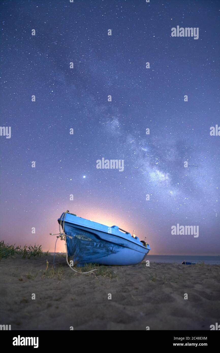 Milky way above a boat on the beach on a calm night Stock Photo - Alamy