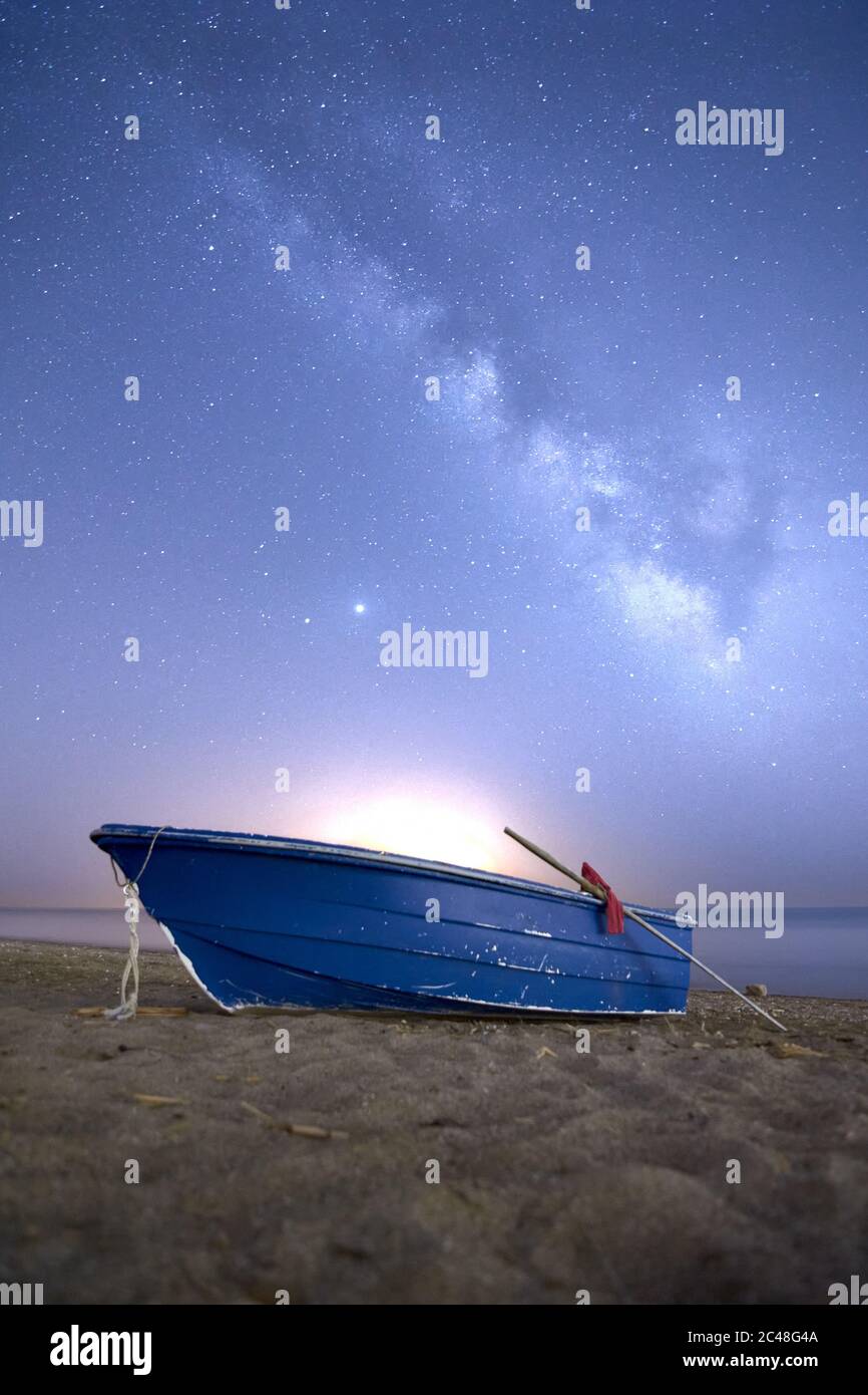 Milky way above a boat on the beach on a calm night Stock Photo - Alamy