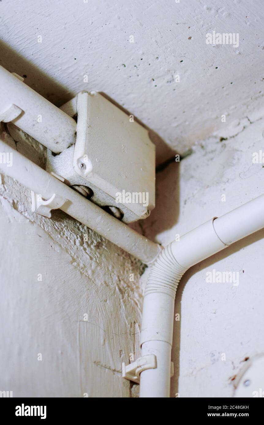 Vertical shot of cables and pipes with a splitter on a white basement ...