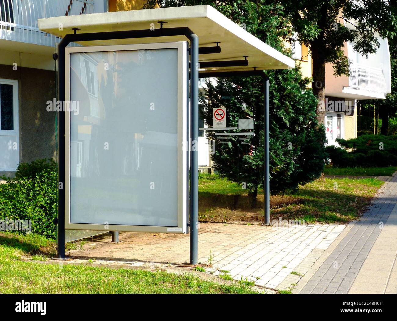 glass structure bus shelter. mock-up background. green lawn and trees ...