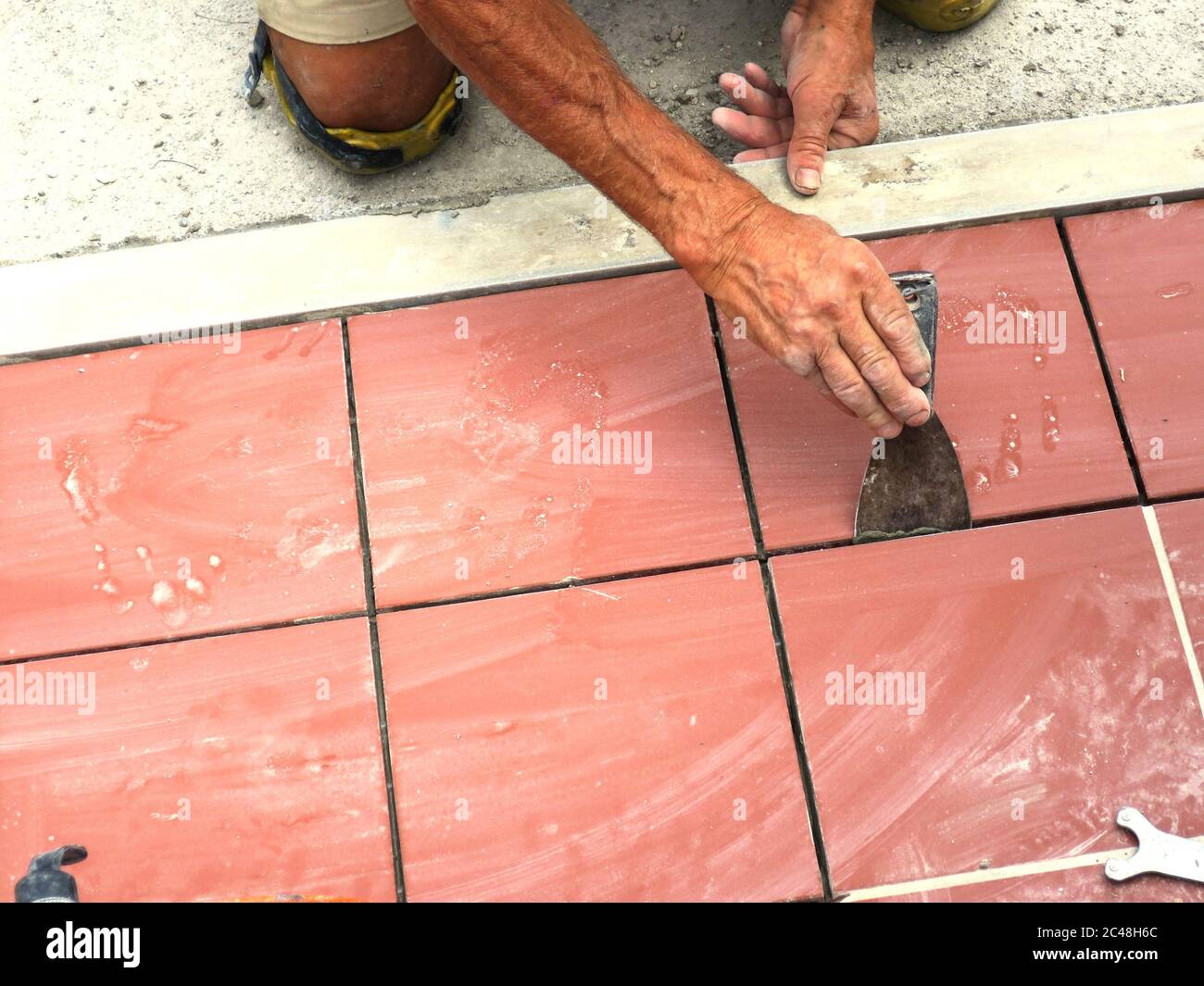 High angle shot of a tiler laying ceramic tiles Stock Photo - Alamy