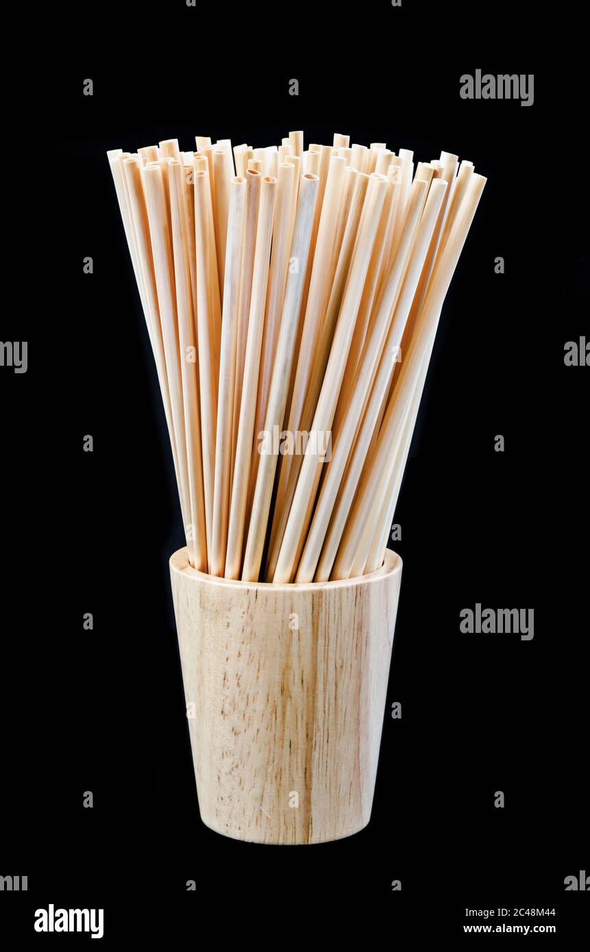 Wheat straw for drinking water in wooden glass on black background ...