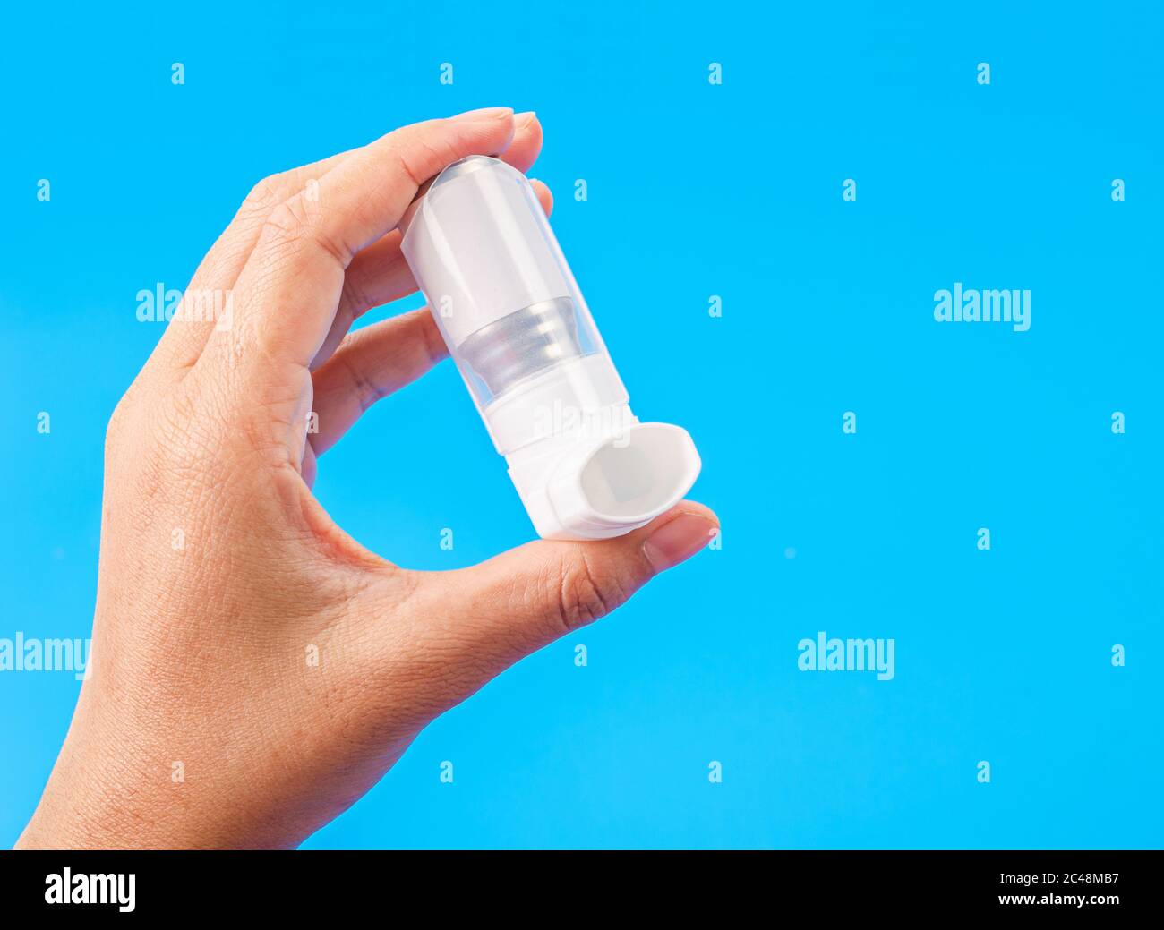 Person holding a white asthma inhaler on blue background Stock Photo ...