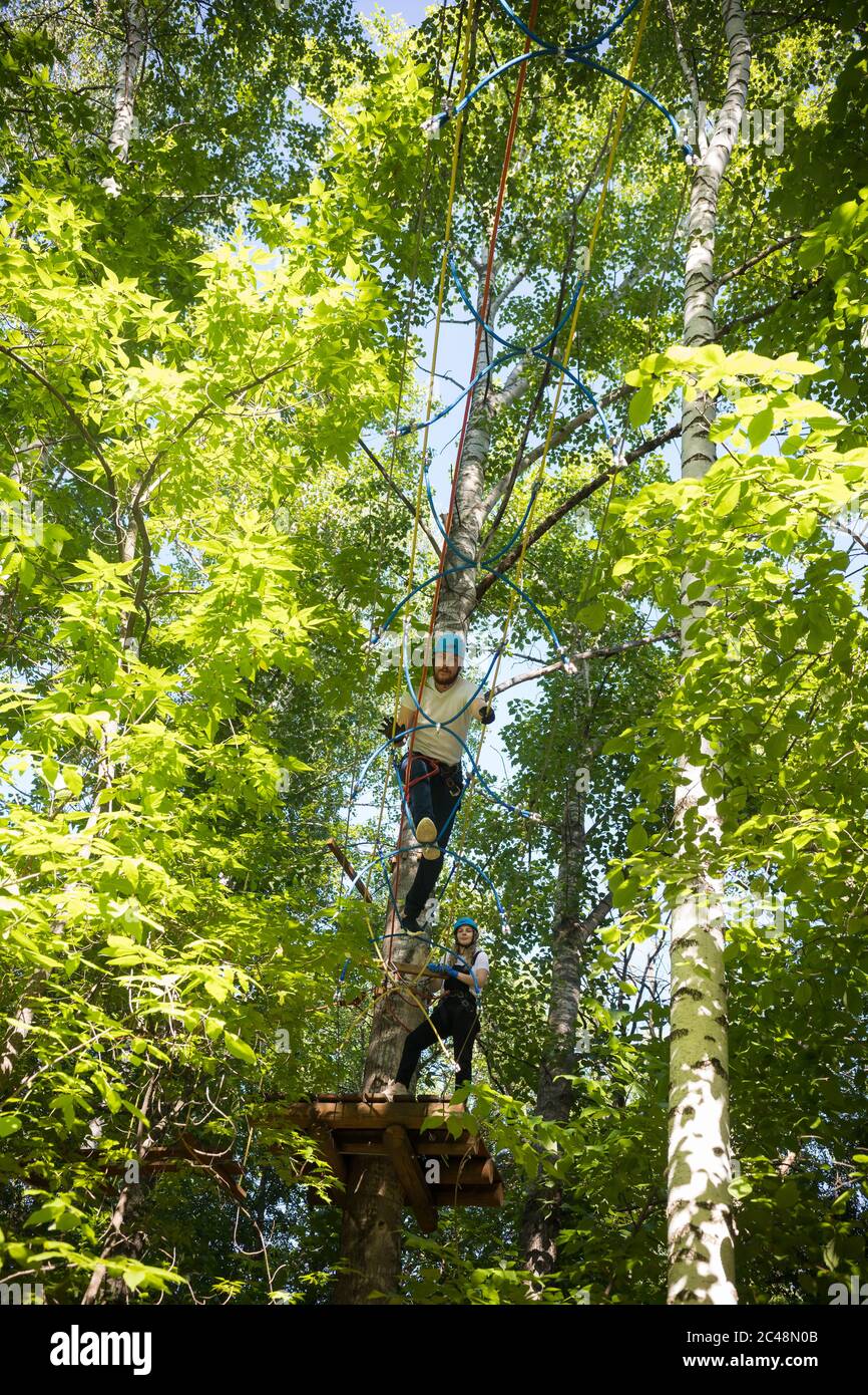 Woman and man having a rope entertainment in the green forest ...