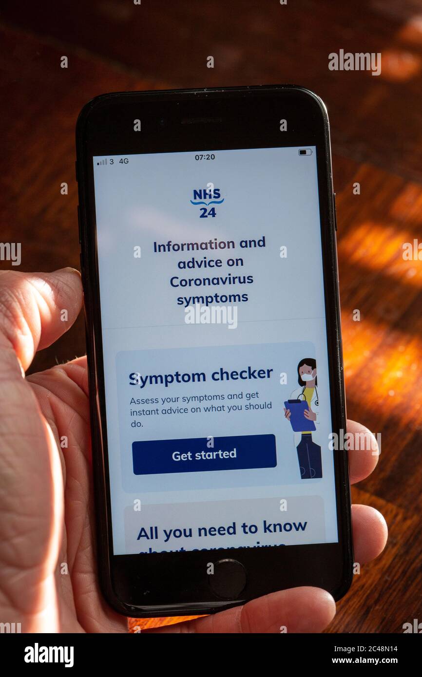 A hand holding a black mobile phone showing the NHS 24 Covid 19 App ...