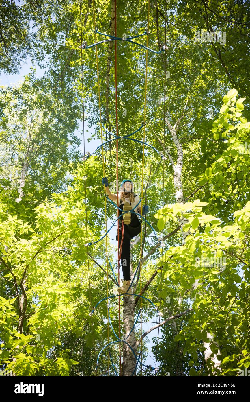Rope adventure - blonde woman crossing the rope bridge. Mid shot Stock ...