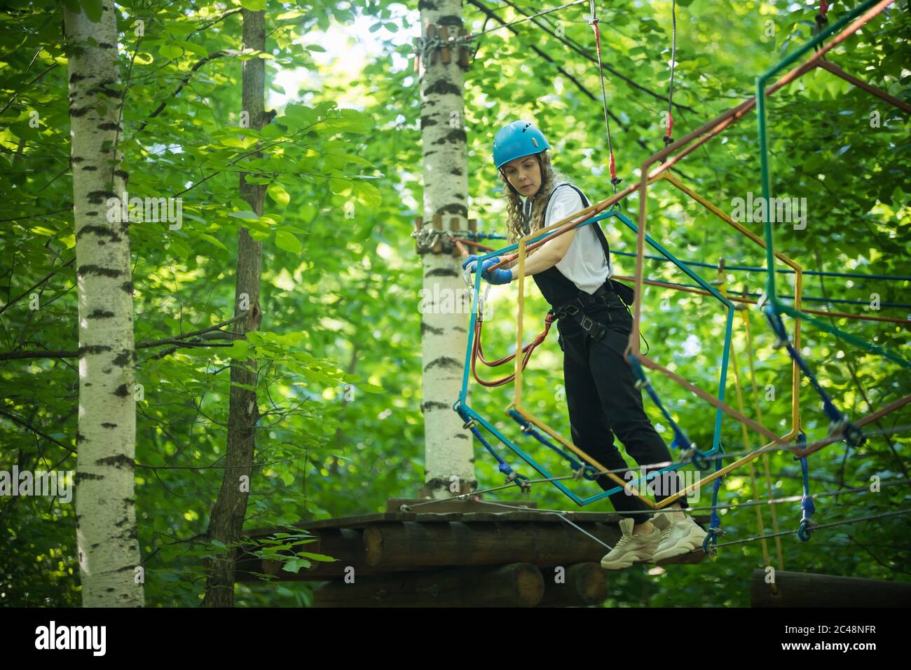 Rope adventure in the forest - woman in blue helmet standing on the ...