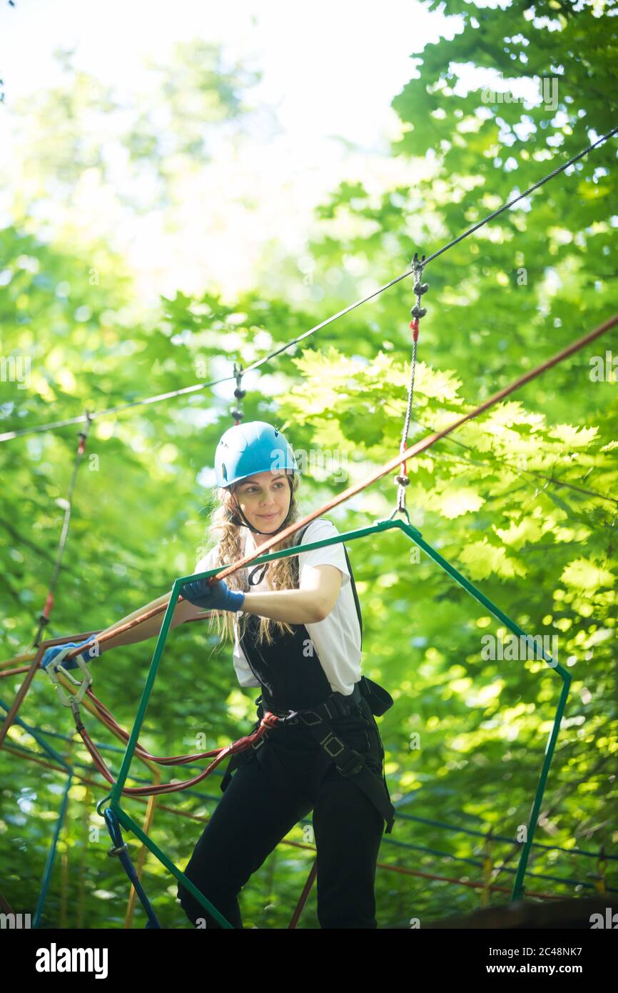 Rope adventure in the forest - woman in blue helmet crossing the rope ...
