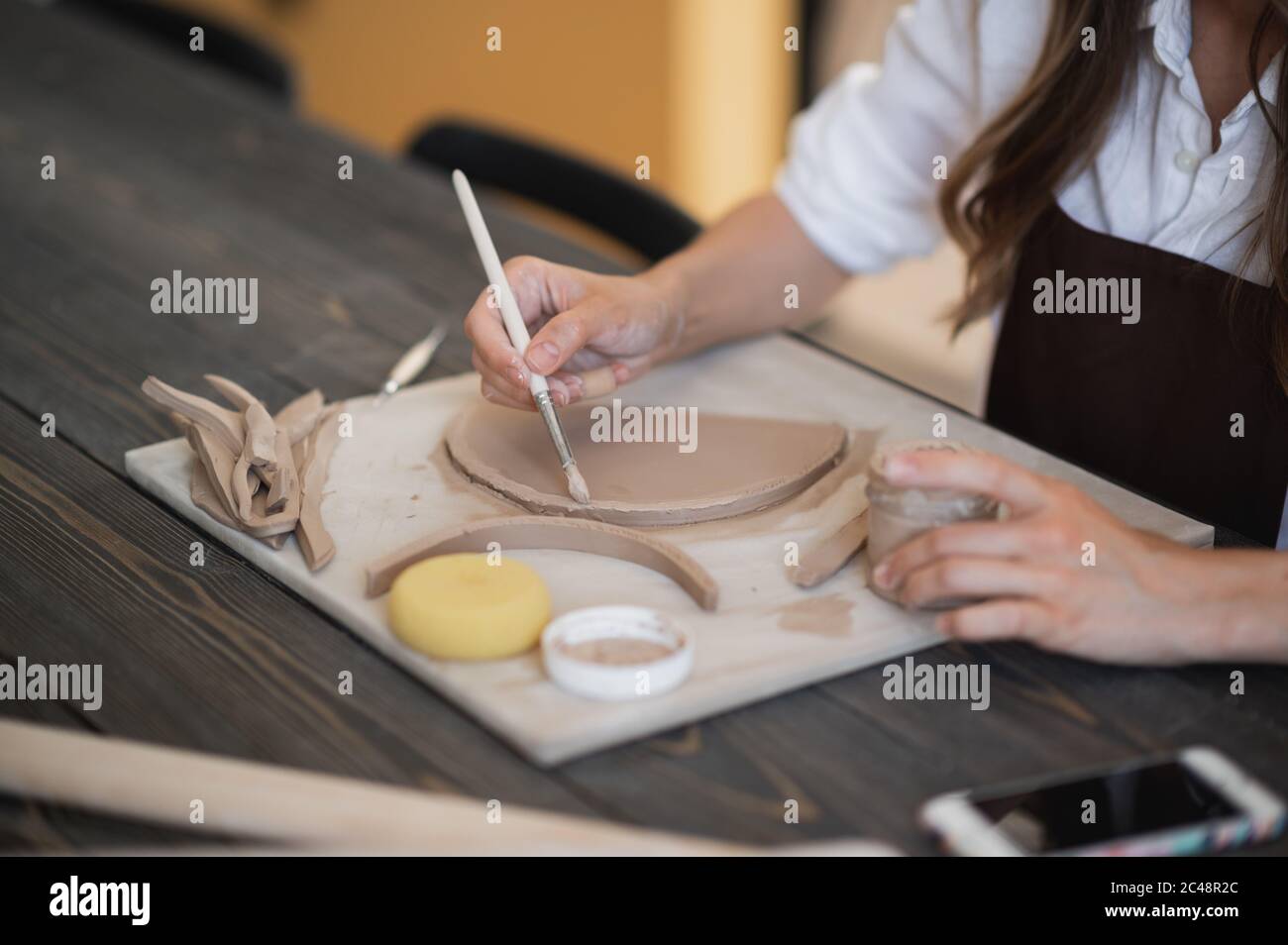 Woman's fingers adding and adjusting a clay part on a future ceramic ...