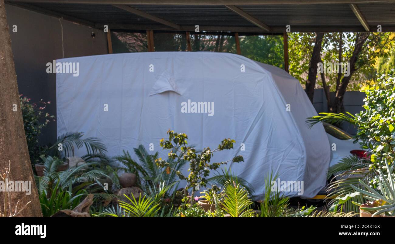 A small caravan covered with a weather outdoor protector parked at a ...