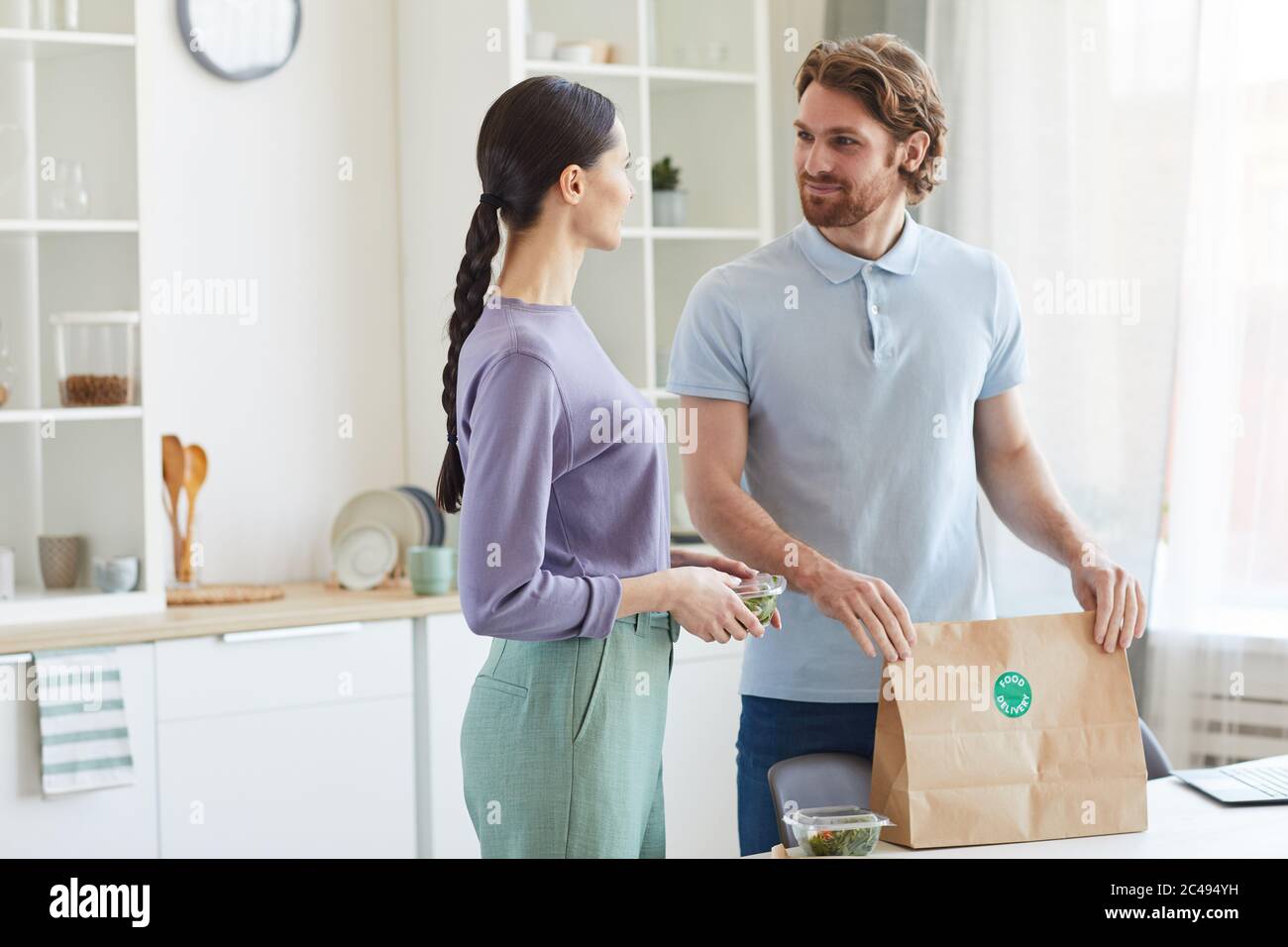 Young couple getting food delivery they standing in the kitchen and ...