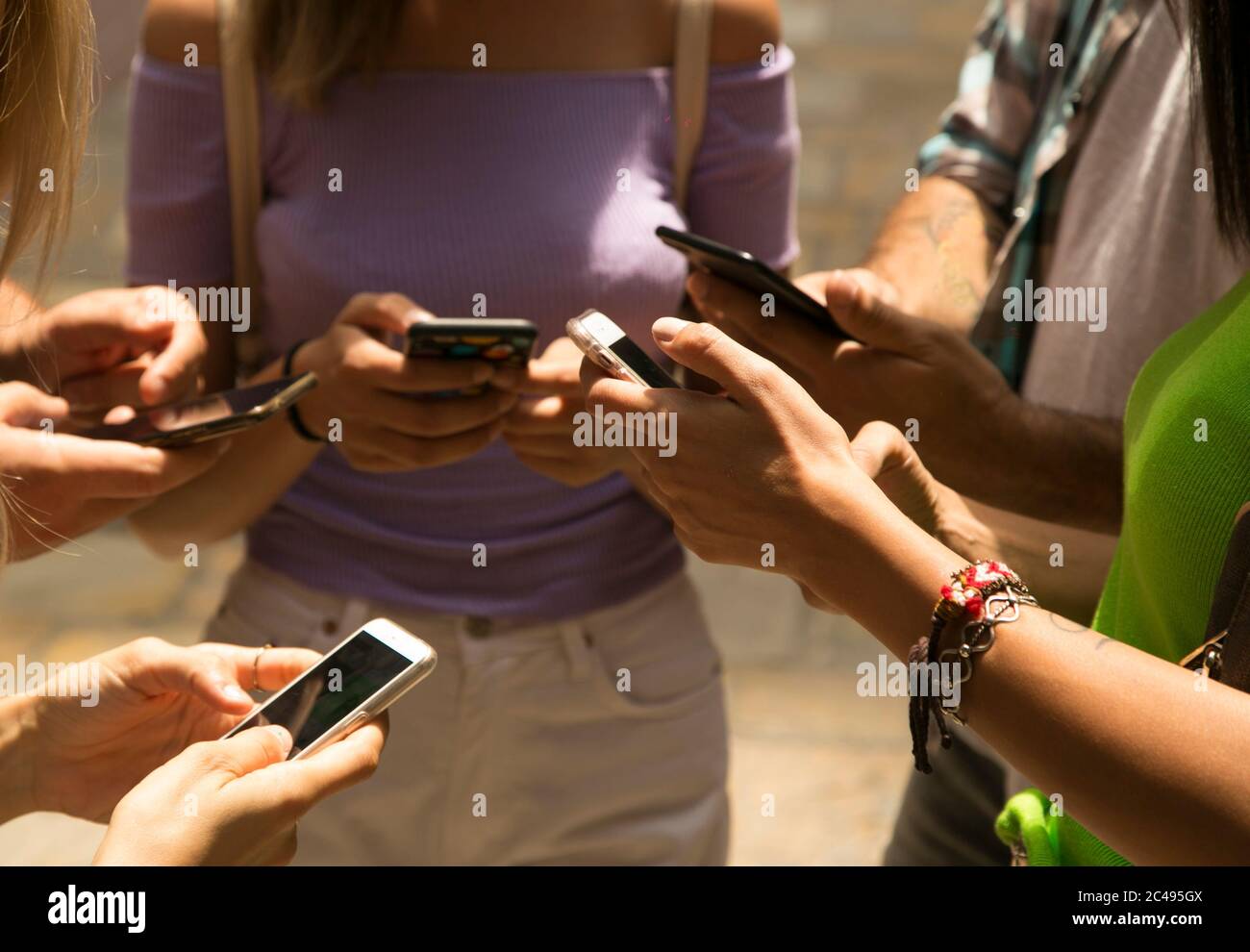 teenager friend group standing outdoor using their smart phone having ...