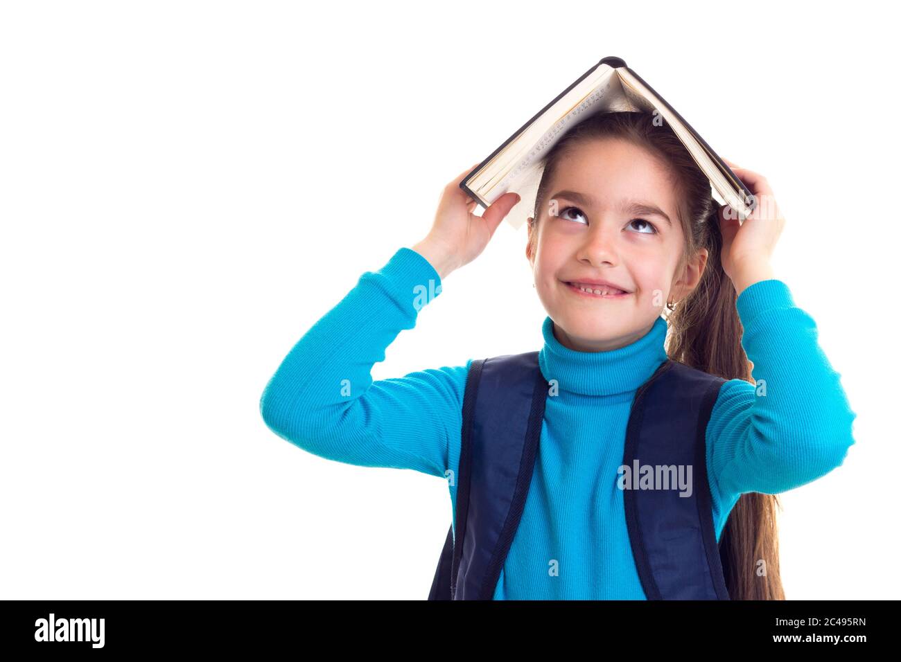 Dreaming schoolgirl with book over head looking up Stock Photo - Alamy