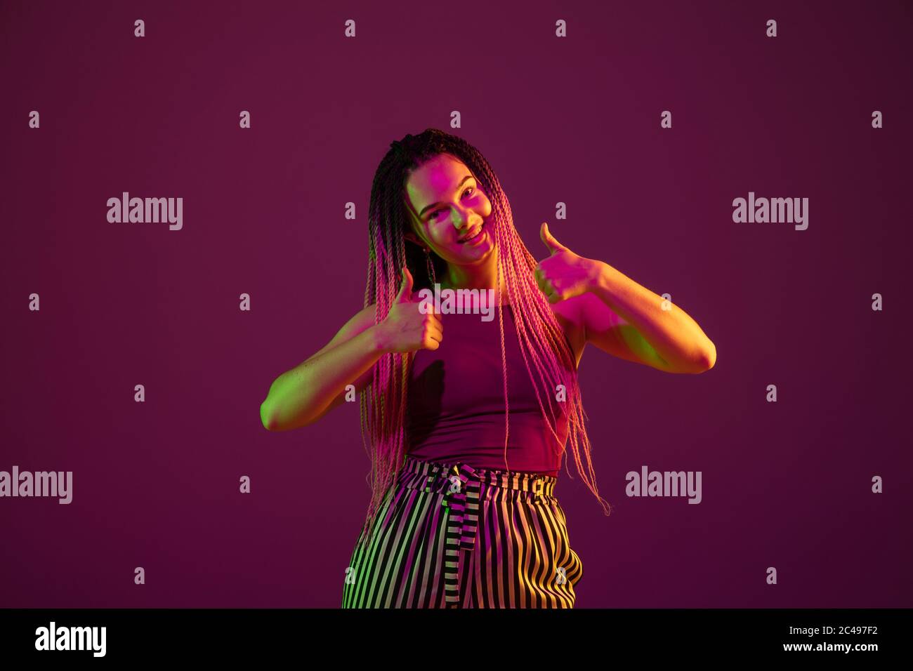 Young caucasian woman showing thumbs up on pink studio background in ...