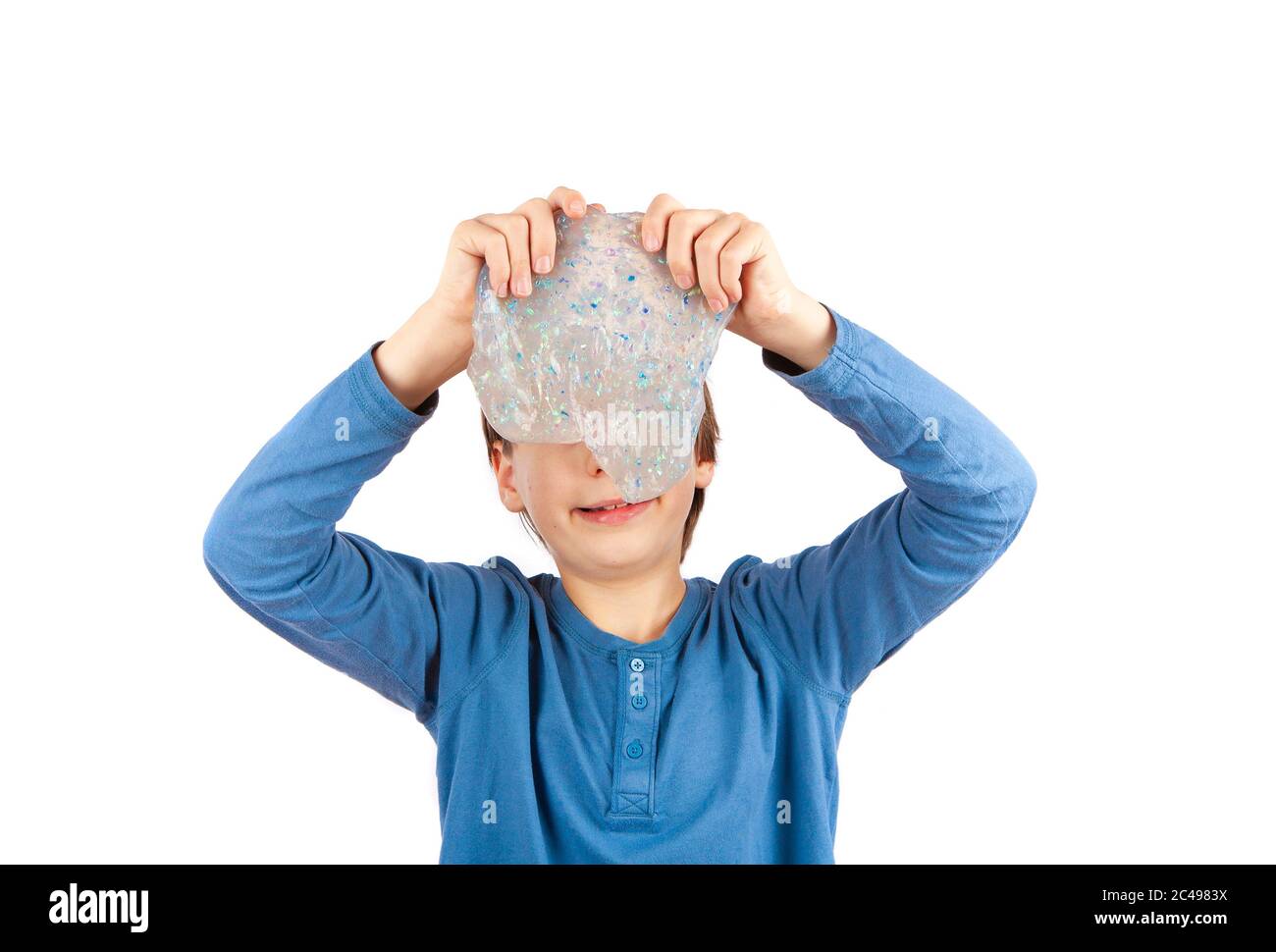 Young boy holdnig a glitter slime in front of his face and smilling ...