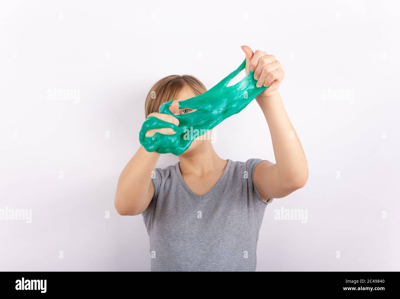 Funny girl holding a slime in front of her face and looking through its ...