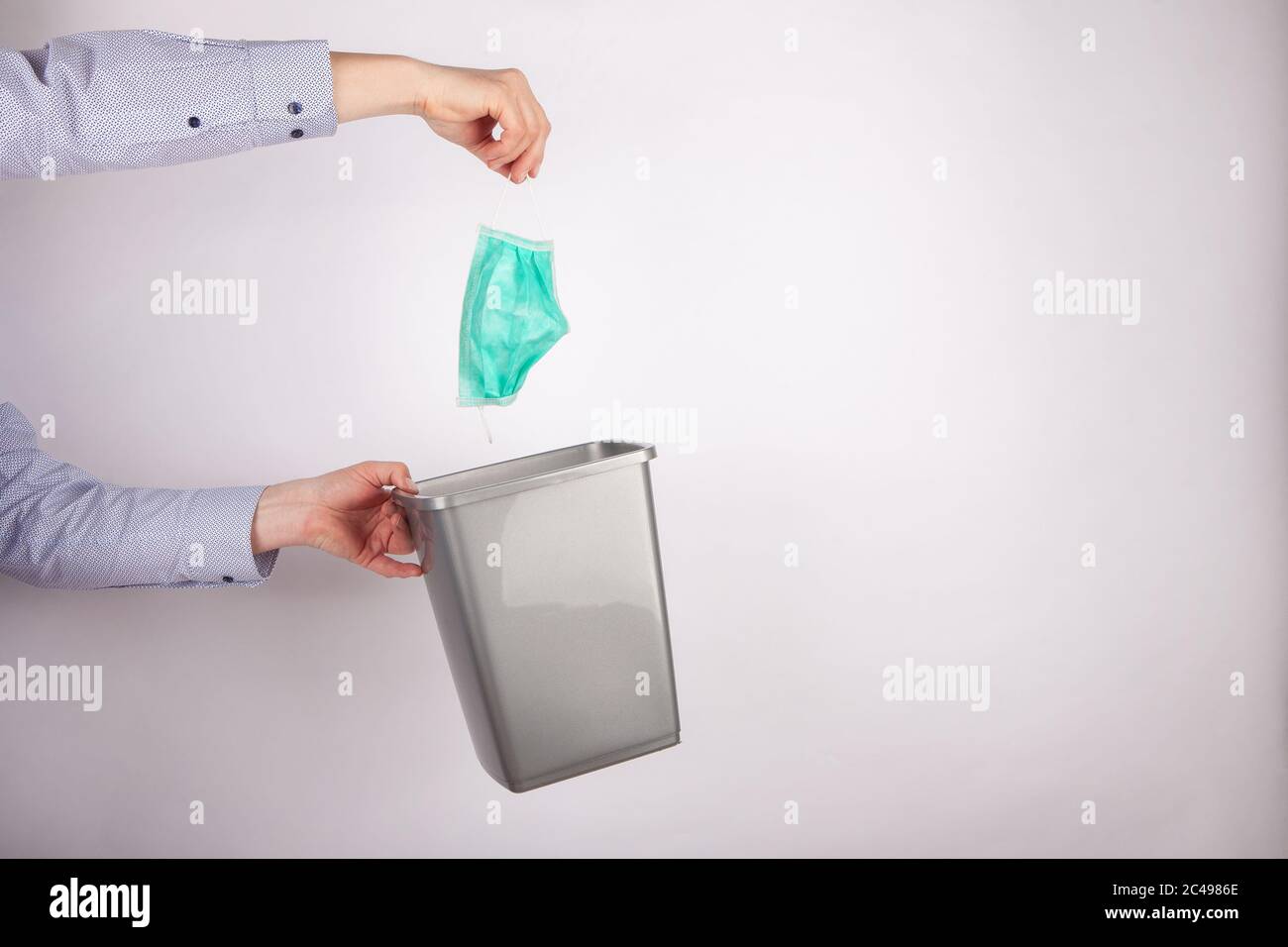 Useless coronavirus face mask - Man hands holding plastic trash can and ...