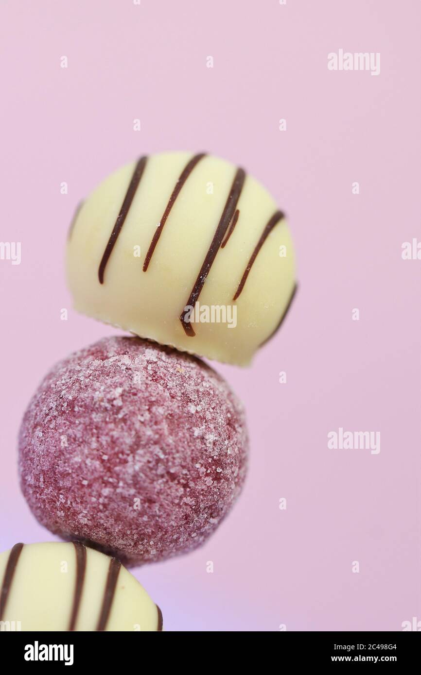White and pink milk chocolate candy row on a blurry pink-lilac pastel ...