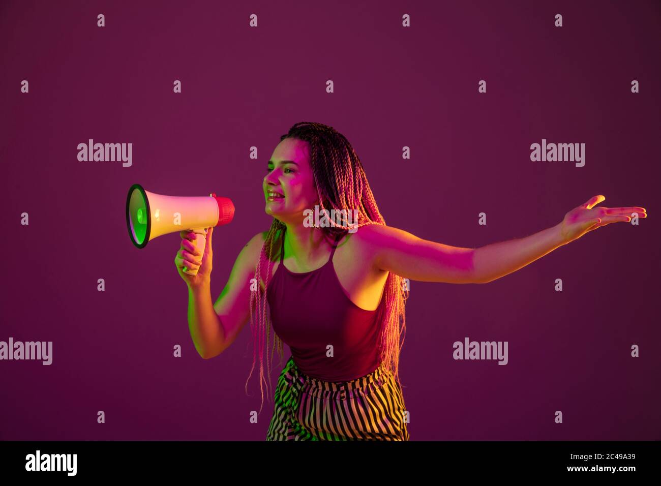 Shouting with megaphone. Young caucasian woman on pink studio ...