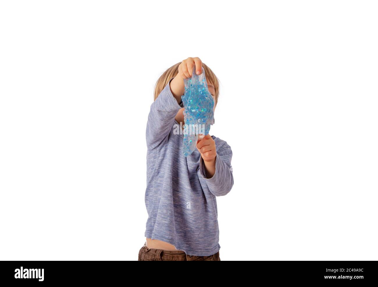 Cute small boy holding a blue glitter slime in front of his face ...