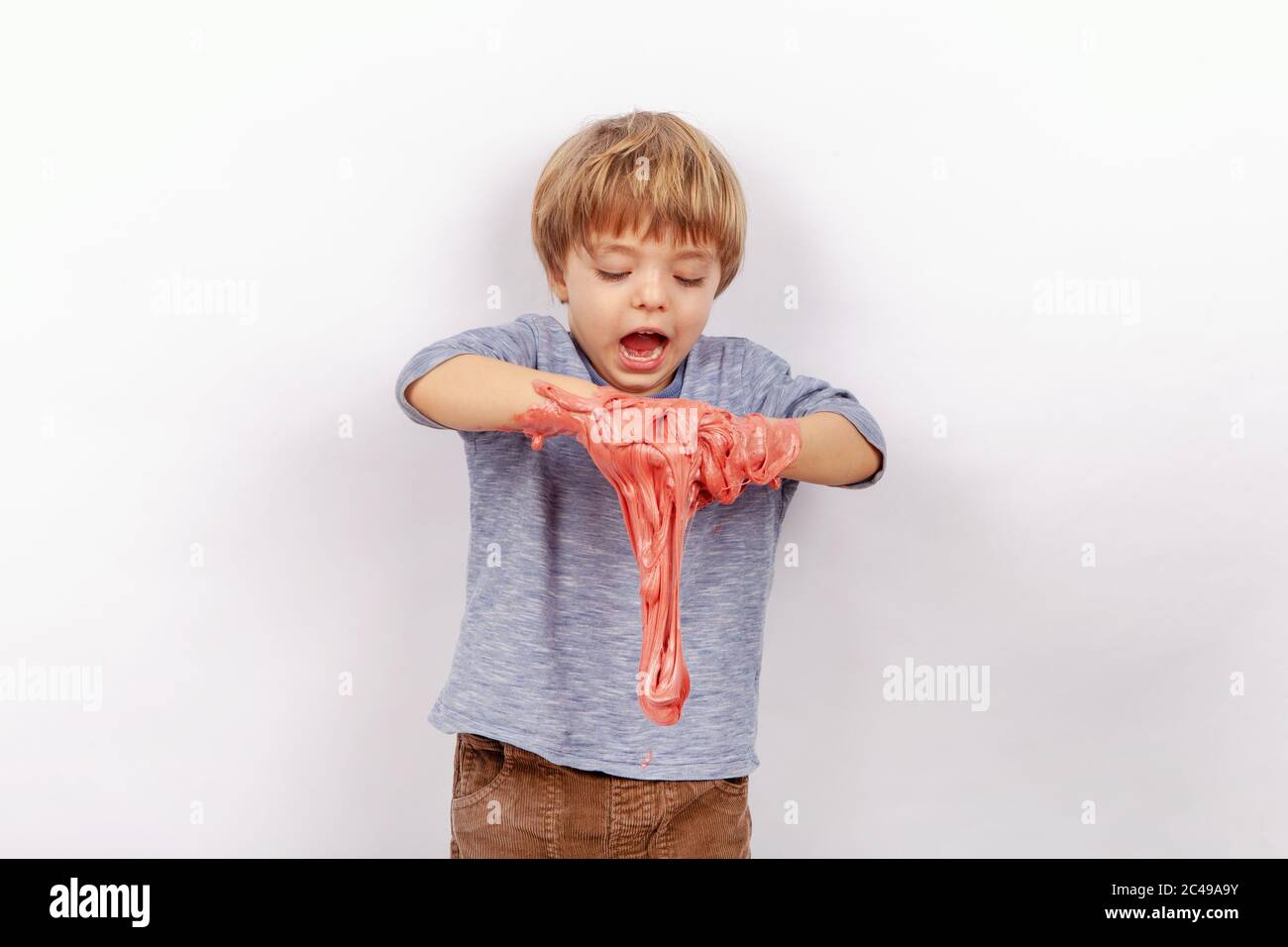 Cute small boy playing with slime looks like a red gunk Stock Photo - Alamy