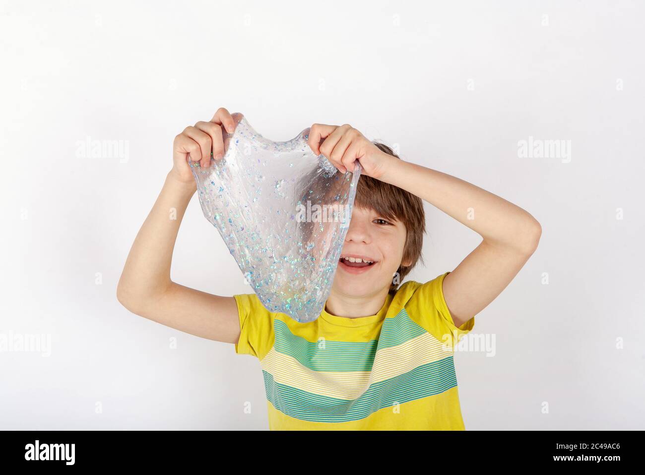 Cheerful boy holding a glitter slime in front of his face Stock Photo ...