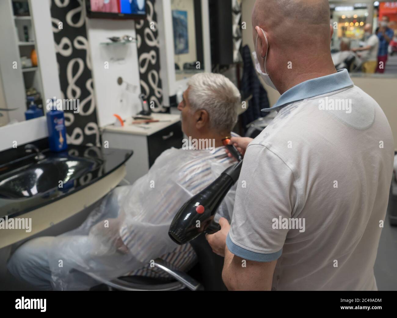 Professional barber in a medical gauze mask on his face making a ...