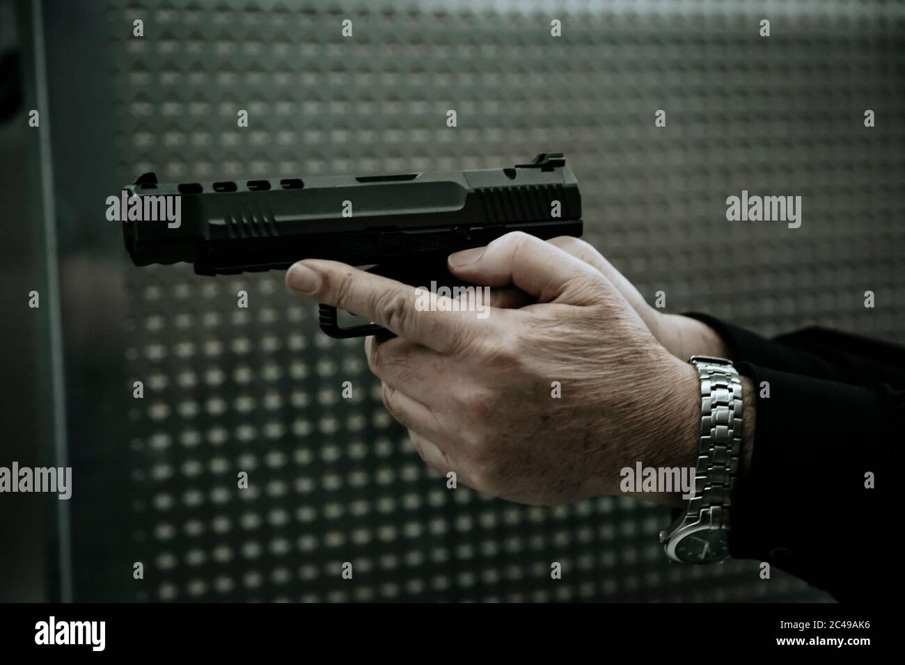 Man aiming pistol at target in indoor firing range or shooting range ...