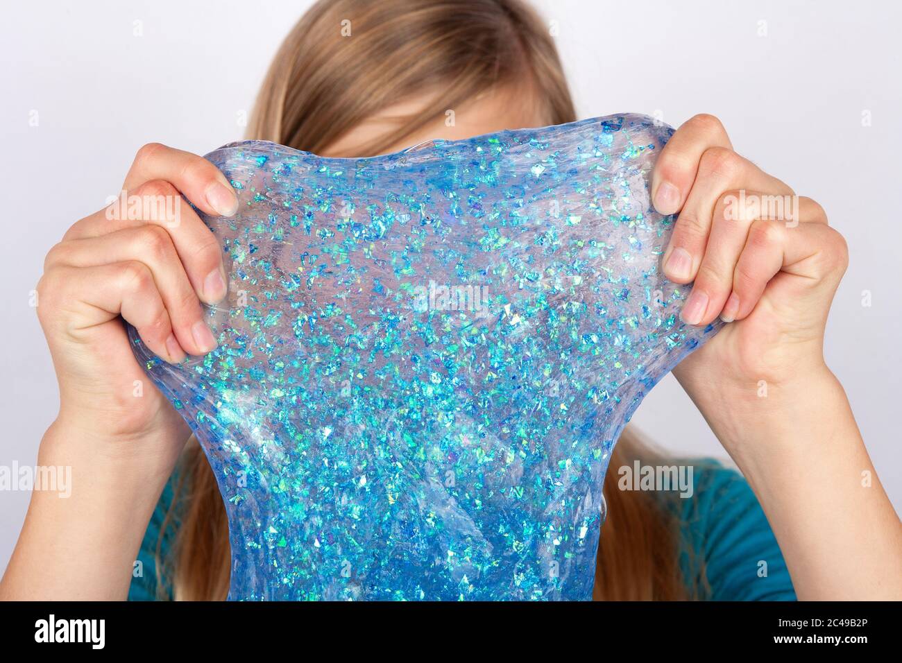 Girl holding blue glitter slime in front of her face Stock Photo - Alamy