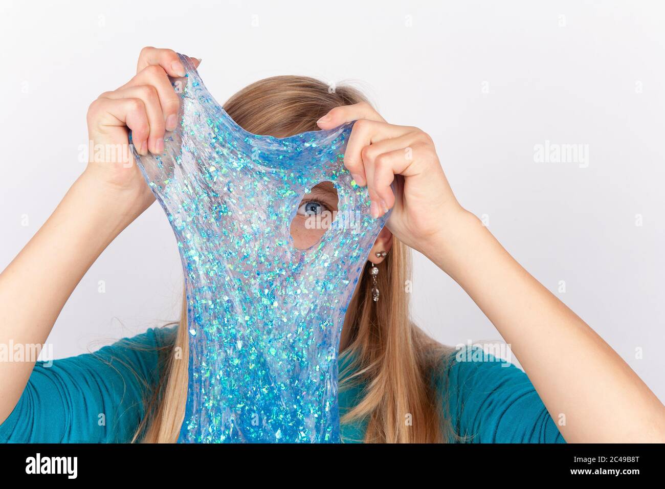 Funny girl holding a blue glitter slime in front of her face and ...