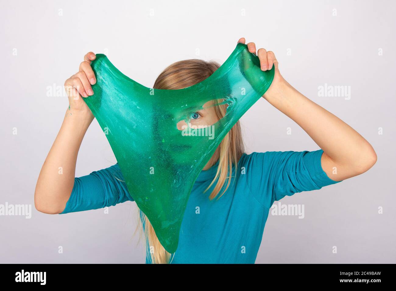 Funny girl holdin a transparent slime in front of her face and looking ...